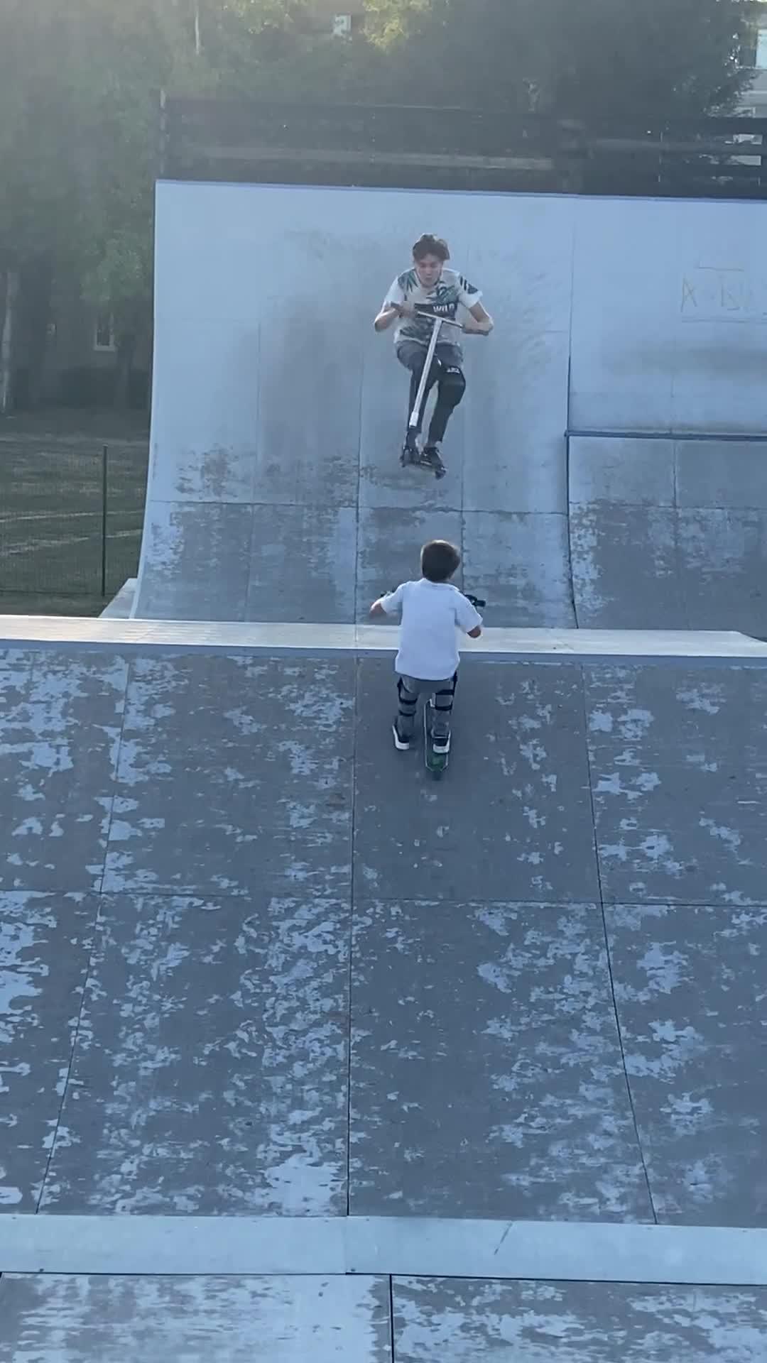 Two Kids Crash Into Each Other While Riding Scooters on Skating Ramp ...