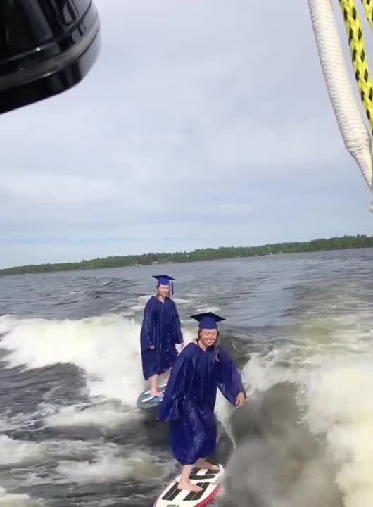 Two Girls Wakesurf While Wearing Graduation Gown and Cap | Jukin Licensing