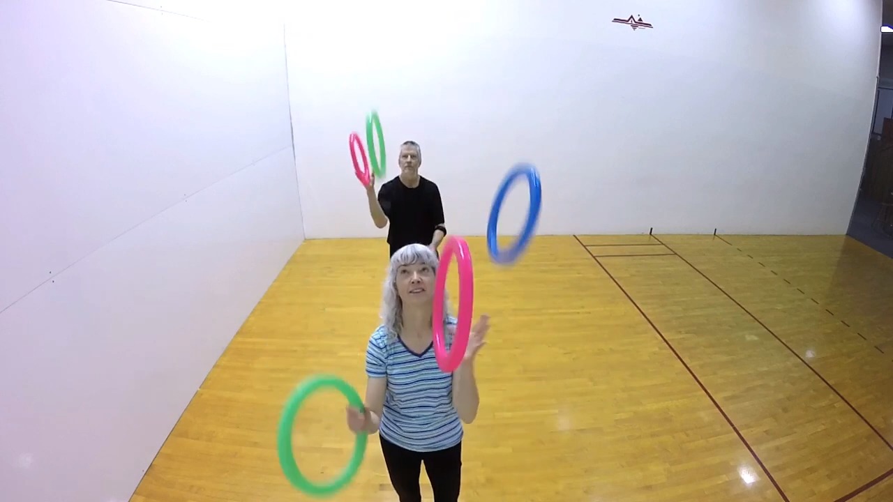 Woman Performs Pass Juggling Trick With Man While Looking Away From Him ...