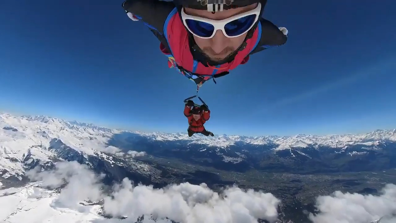Guy Performs Base Jump Over Swiss Mountains and Holds on to Another Guy ...