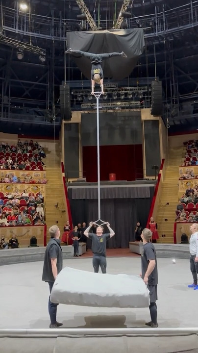Circus Artists Balances Atop Giant Rod While Partner Balances Rod on ...